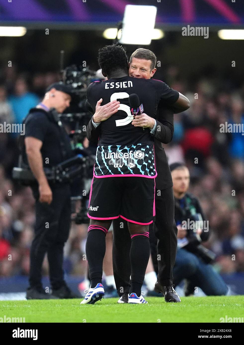 World XI's Michael Essien (left) embraces presenter Dermot O'Leary ...
