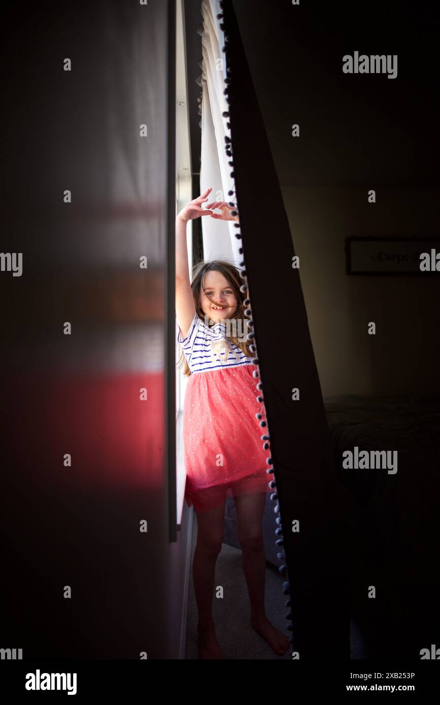 Happy little girl dancing behind curtain indoors Stock Photo - Alamy