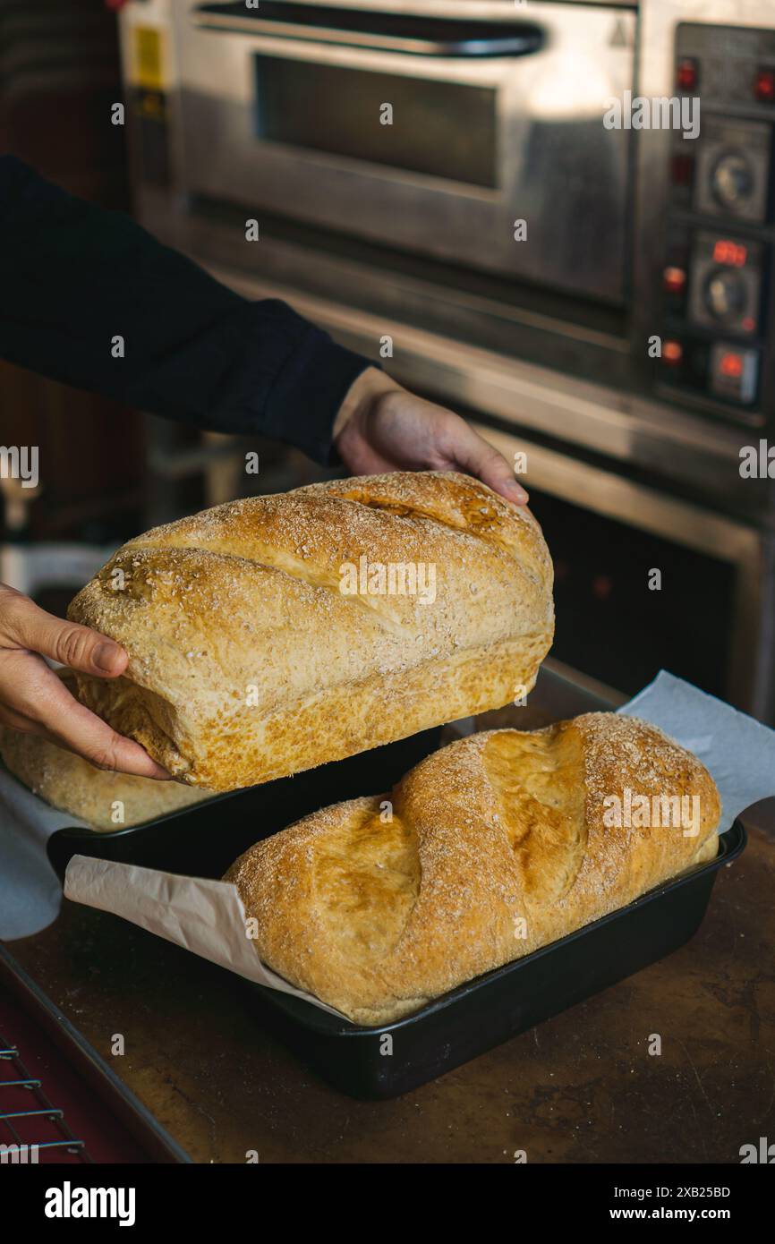 Close up of baker is taking off rye wheat bread from oven, small ...