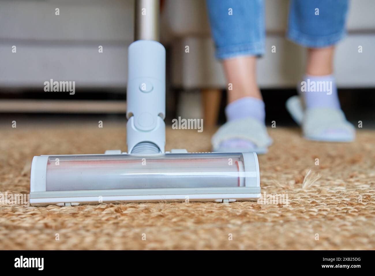 Close up of vacuum cleaner brush cleaning carpet on floor. Woman using ...