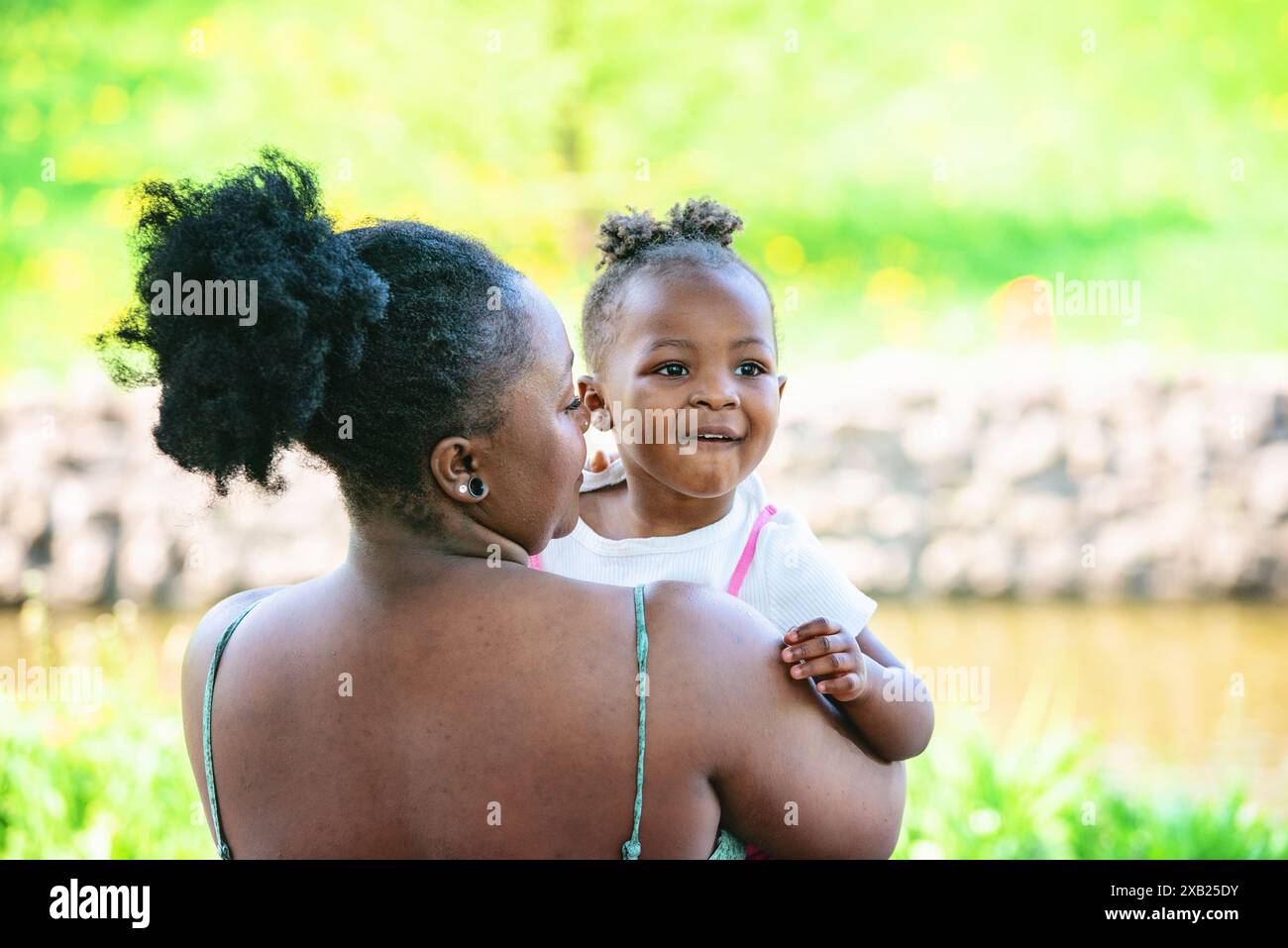 Cute toddler girl looking over Mother's shoulder Stock Photo - Alamy
