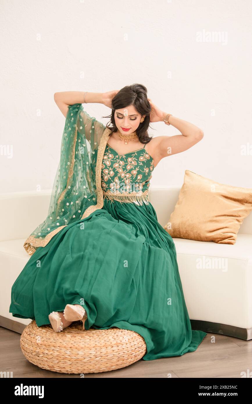 Indian women sitting on couch in her green and gold saree lookin Stock ...