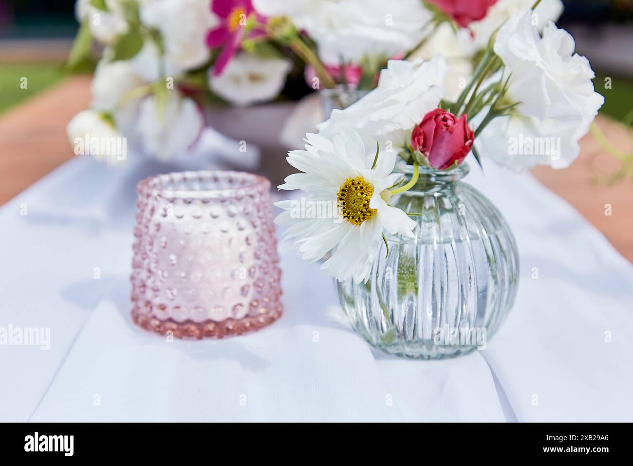Pink candle and bouquet of flowers. Cozy and inviting atmosphere, summer picnic table setting ...