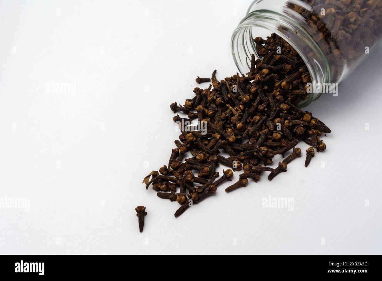 cloves spill out form glass jar, isolated on a white background, spice ...