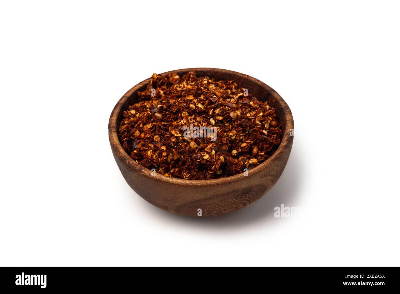 dried chili flakes in a wooden bowl, isolated on white background ...