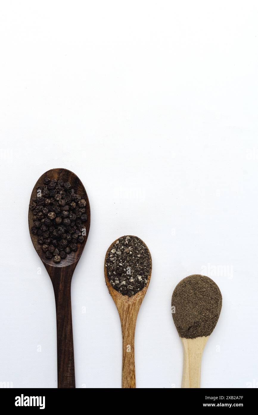 whole, coarse and finely ground black pepper on wooden spoon, isolated ...