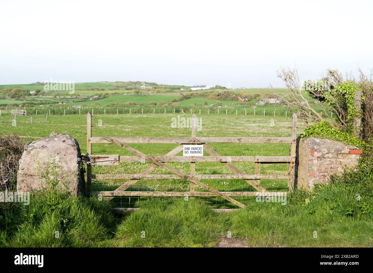 A wooden gate, giving access to a rural field in Wales. There is a sign ...