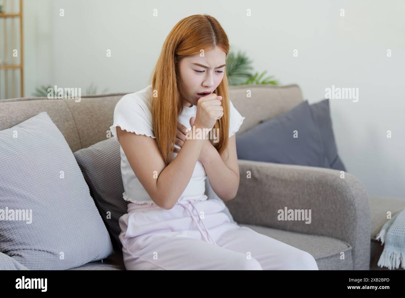 Young Woman Feeling Unwell at Home, Coughing and Holding Chest While ...