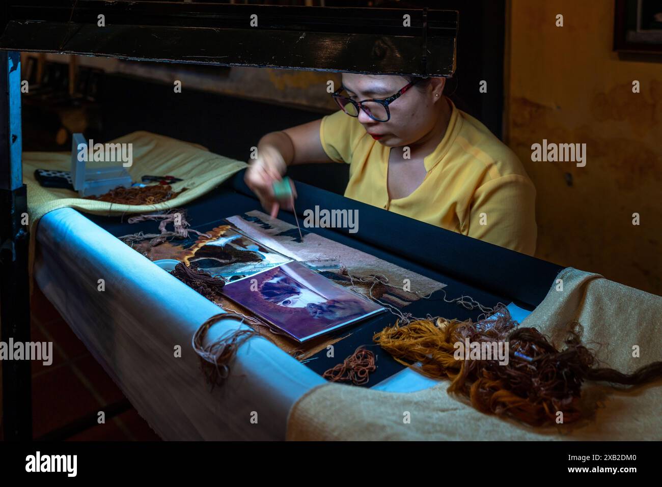 Young Asian embroideress working hard on a handmade embroidery. Embroiderer demonstrating native ...