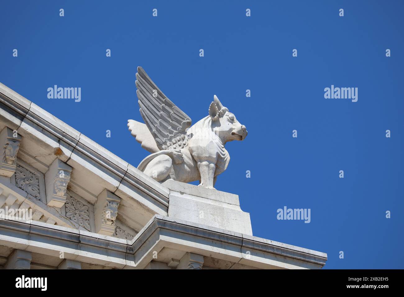 A detailed statue of a winged bull perched on the edge of an ornate ...