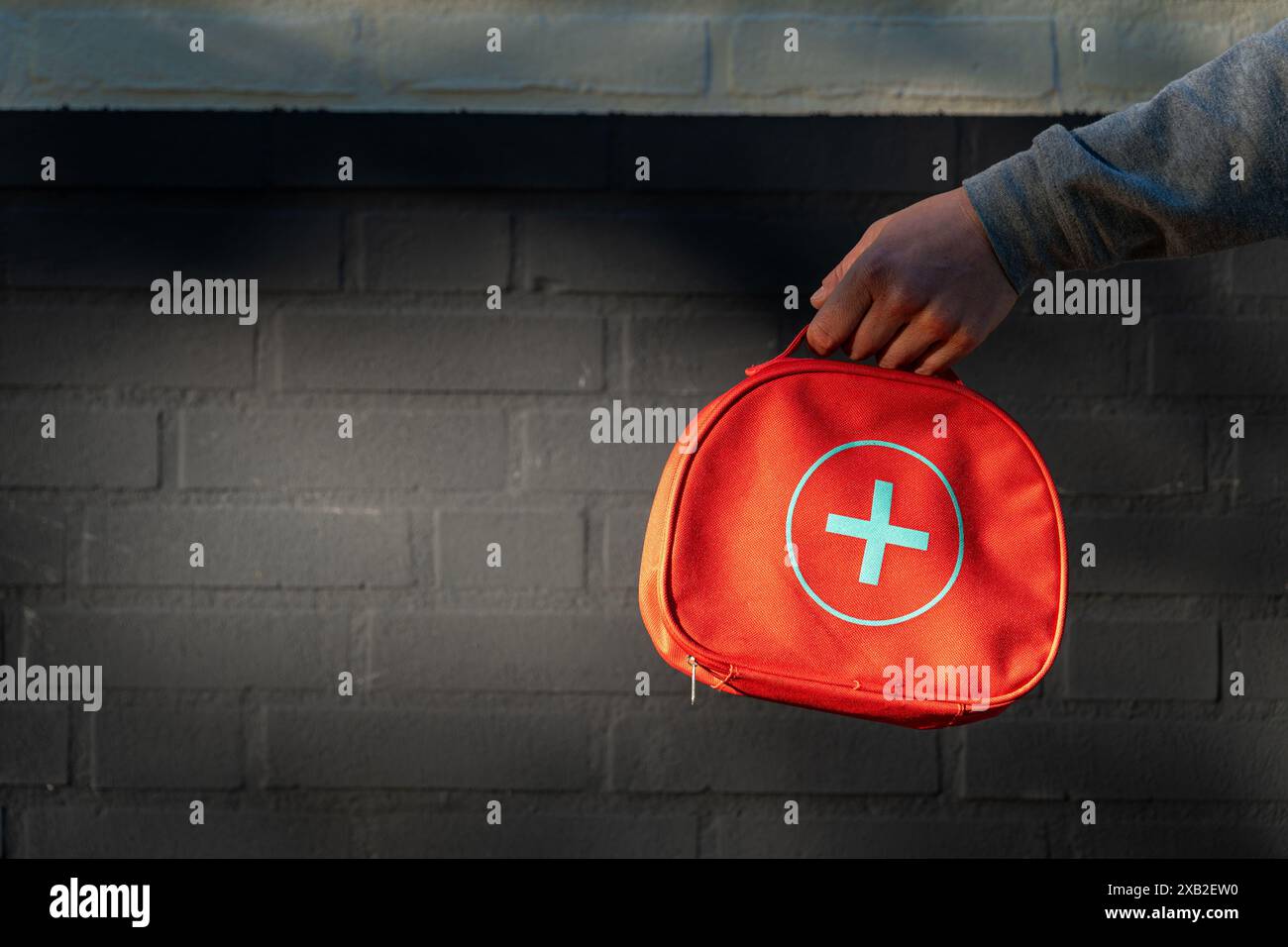 A hand holding first aid kit bag for emergency situations. A red first ...