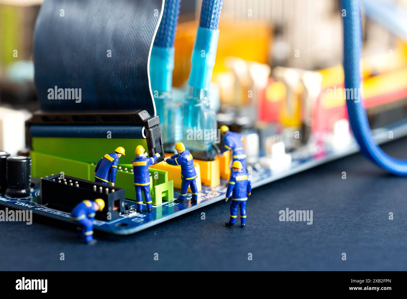 Tiny figurine workers repair and maintain a computer motherboard ...