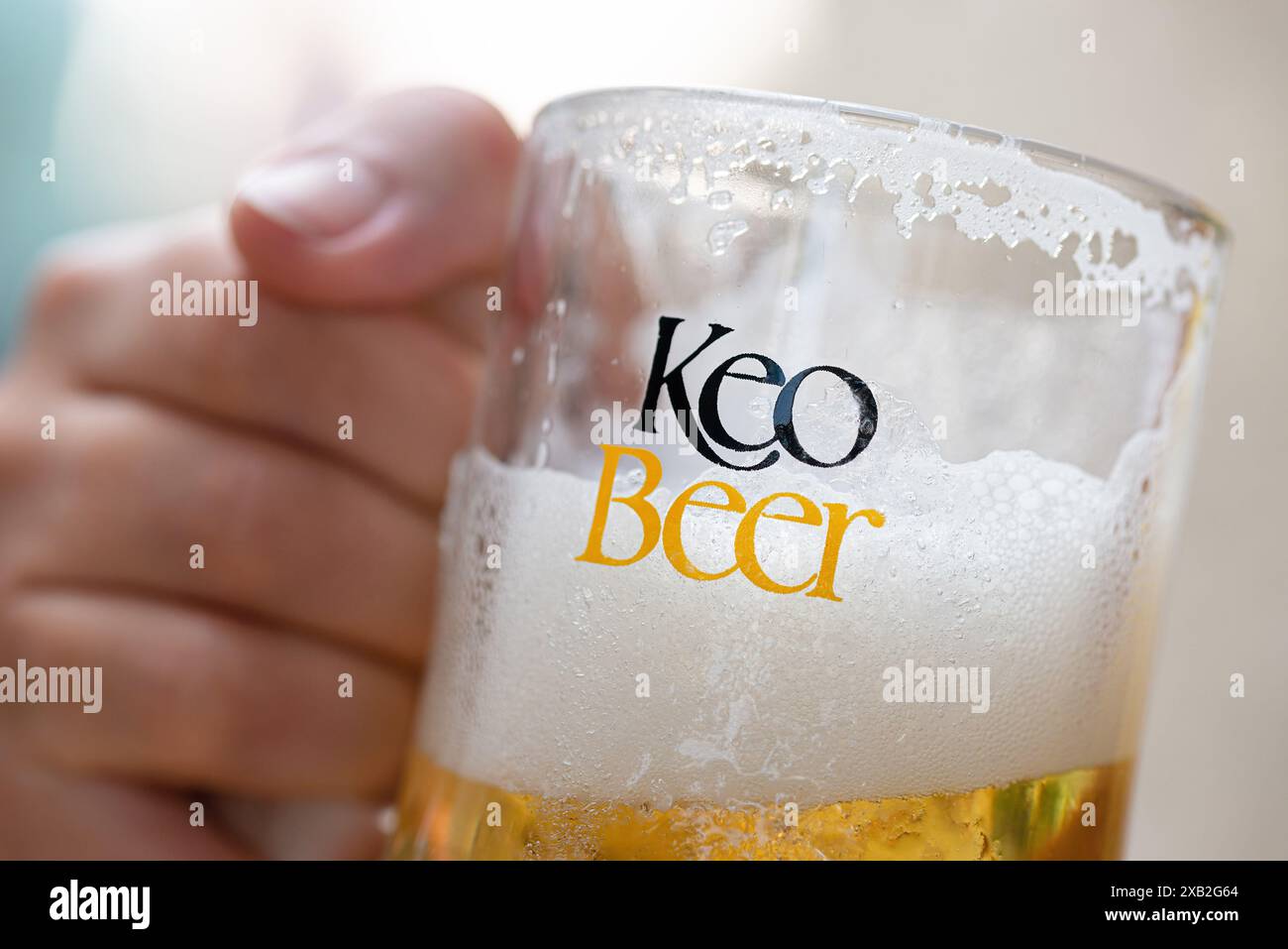 Lania, Cyprus - May 13, 2023: Hand holding a refreshing glass of KEO ...