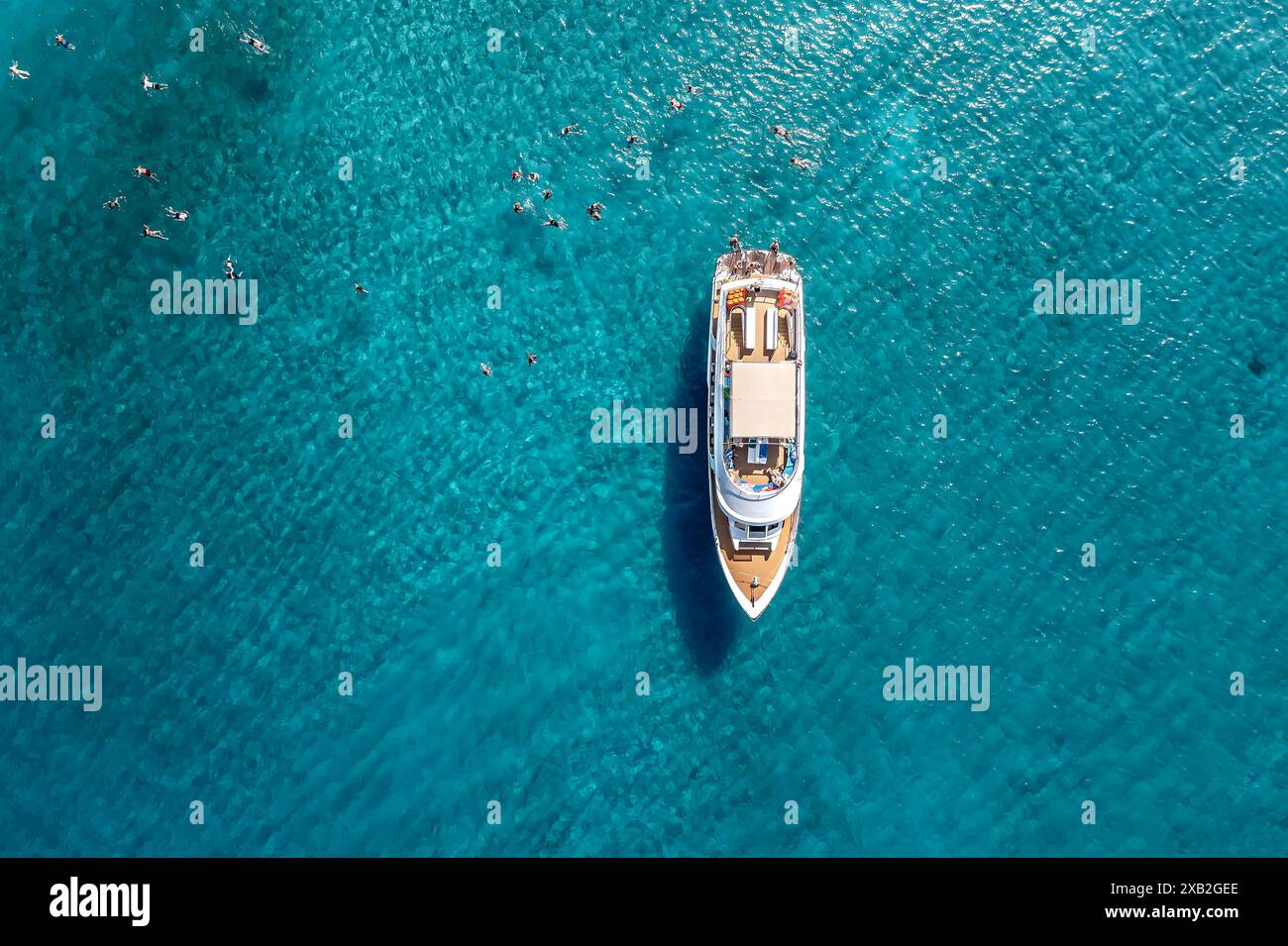 Top-down shot of a boat surrounded by swimmers in the sparkling ...