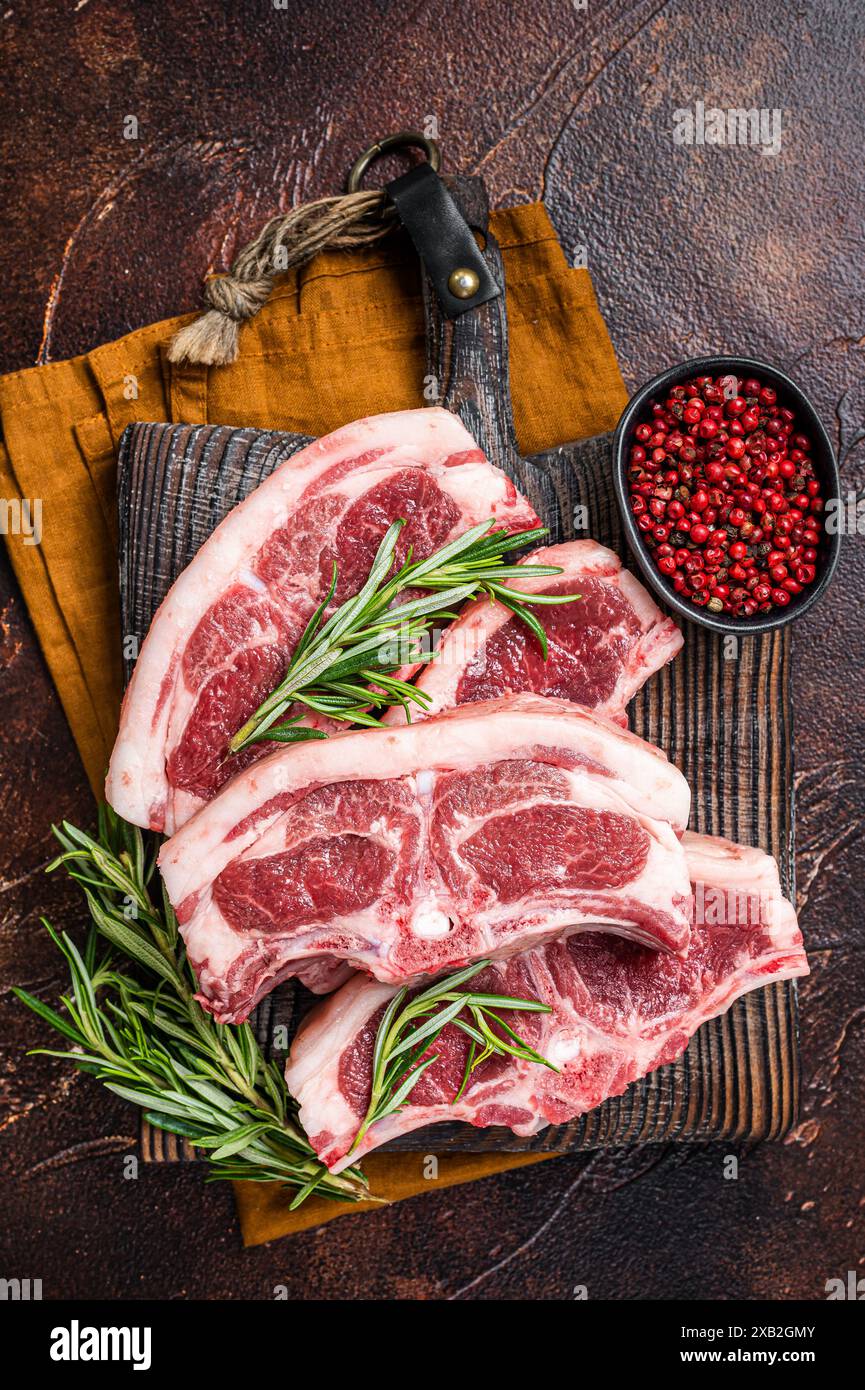 Raw fresh saddle of lamb mutton with herbs and spices on butcher board ...
