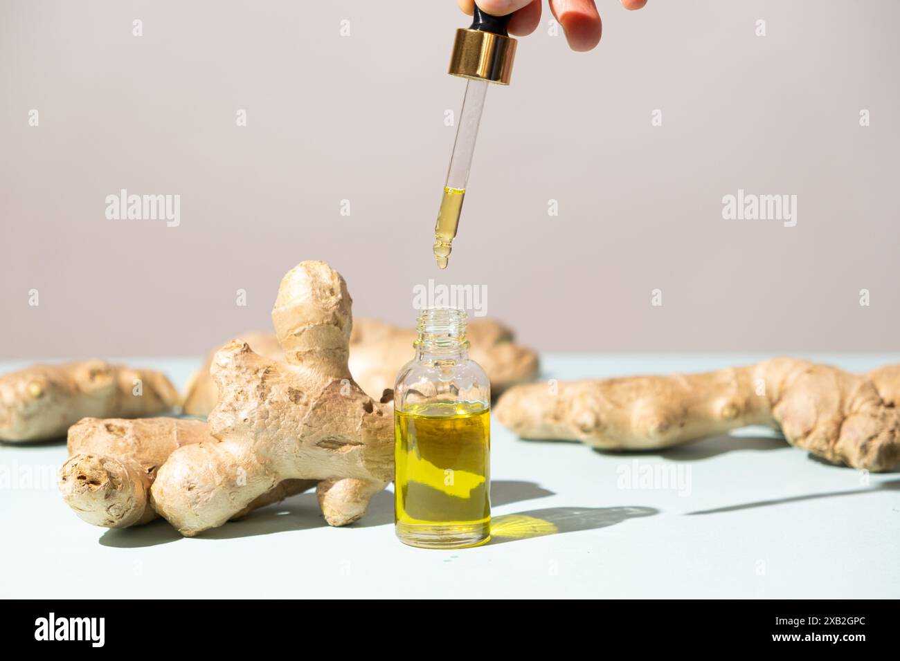 Natural ginger essential oil dripping from pipette into glass bottle Stock Photo - Alamy