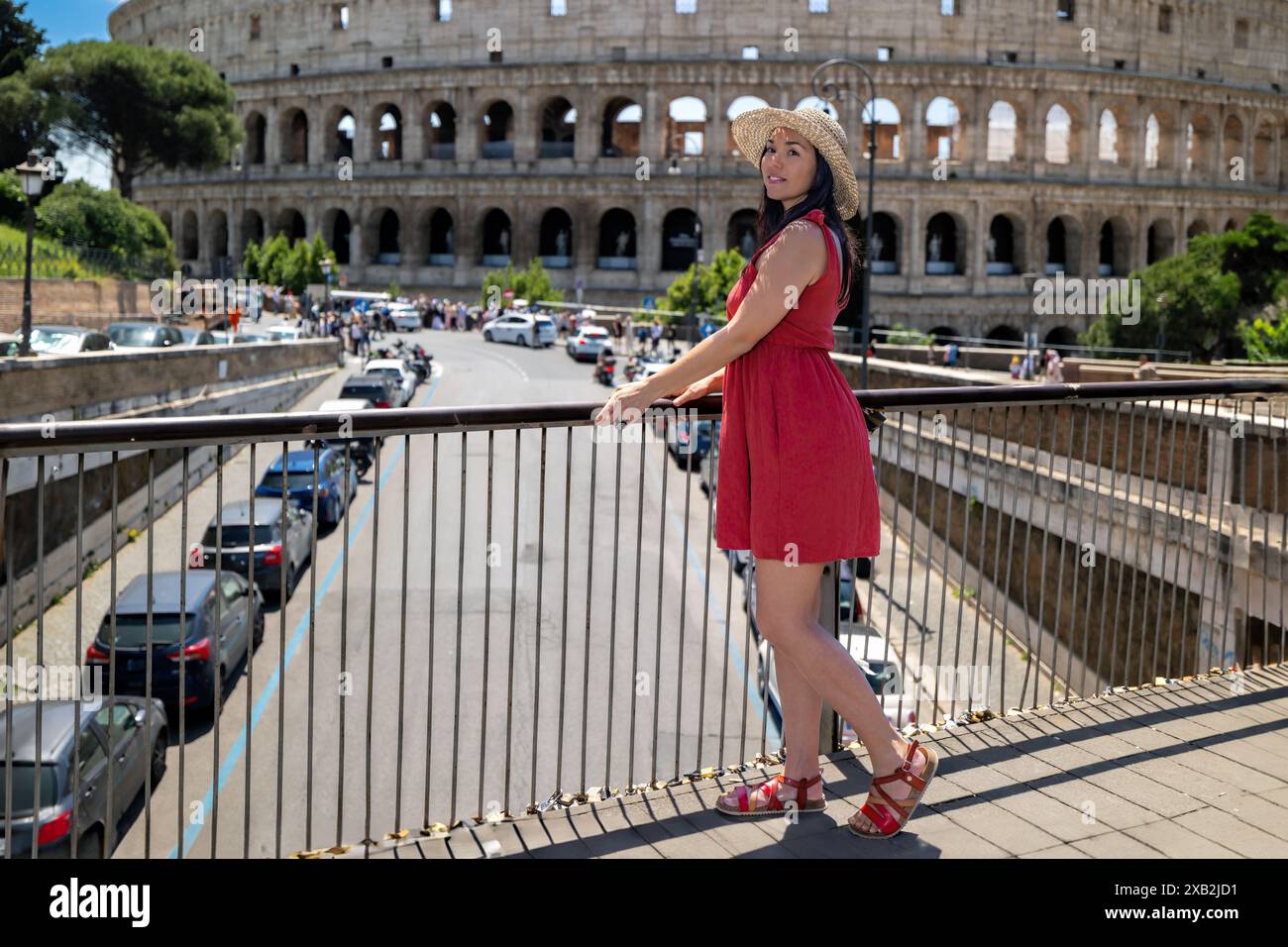 Brunette girl in a straw hat and a red dress admires the ancient ...