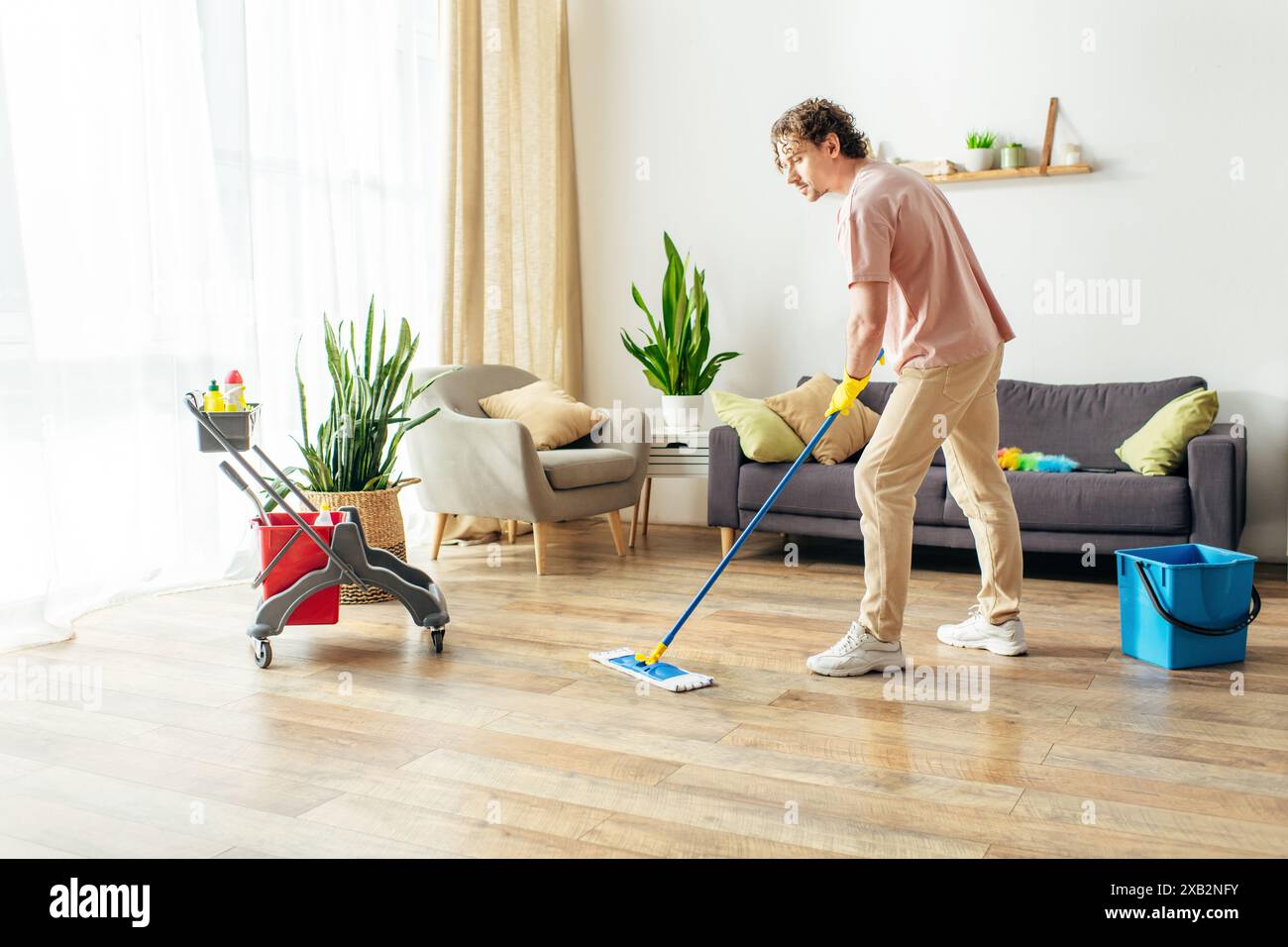 Man in action, mopping living room floor with a mop Stock Photo - Alamy