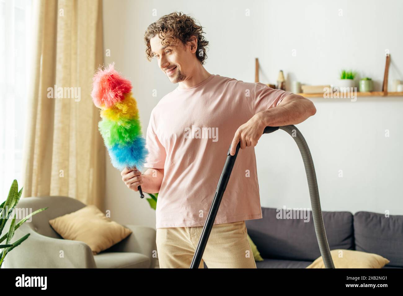 A handsome man in cozy homewear happily holds a bright, colorful duster ...