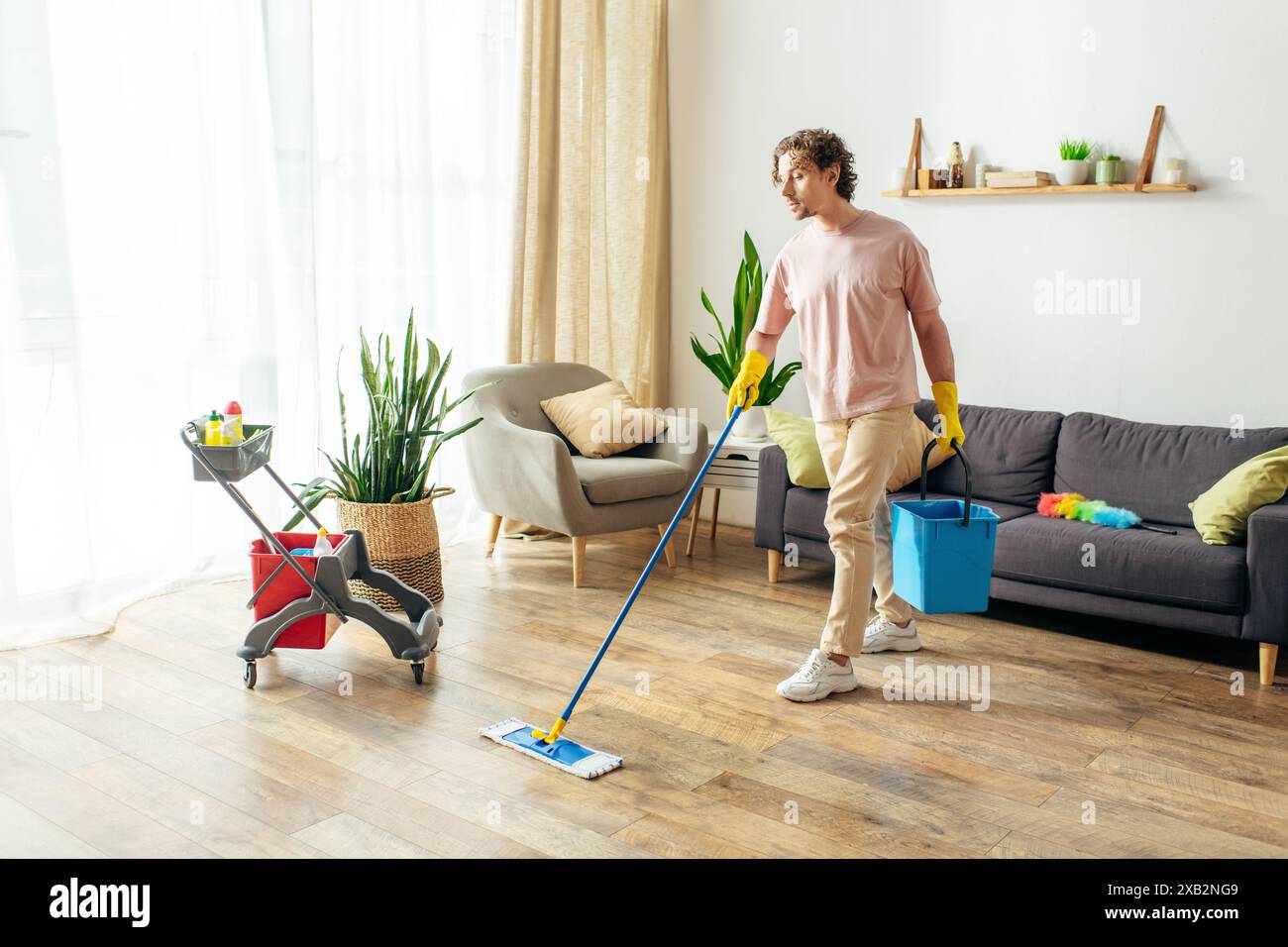 A man in cozy homewear cleaning his living room with a mop Stock Photo ...