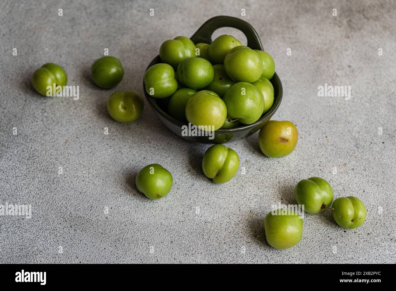 Fresh organic green plums in a dark bowl, a staple ingredient in ...