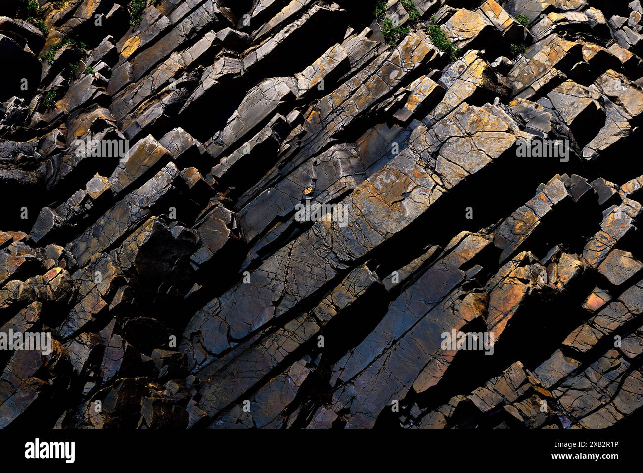 A detailed view of rugged, jagged rock formations, showcasing dark and ...
