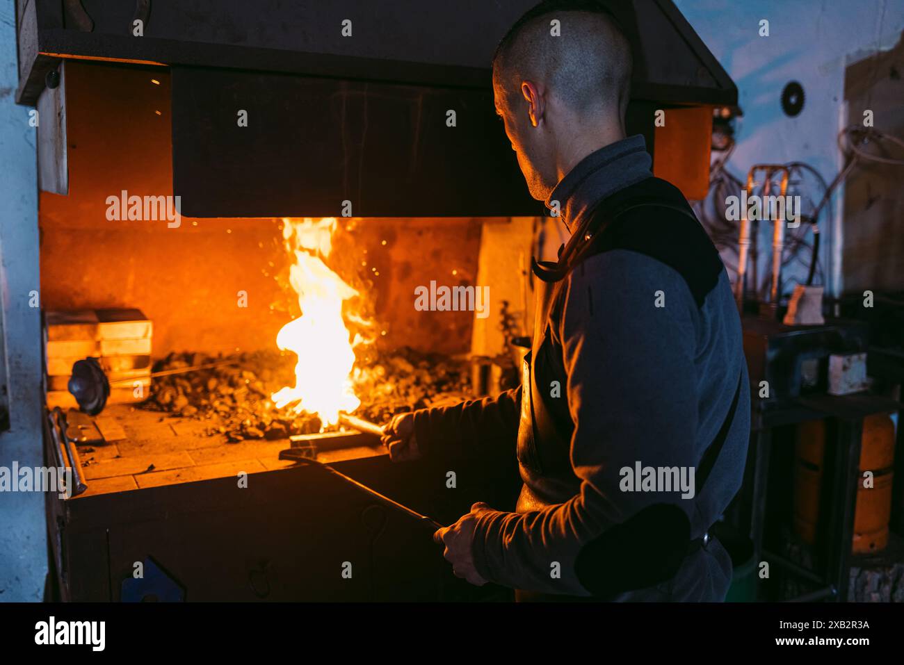 Back view of unrecognizable male blacksmith works with intense focus ...