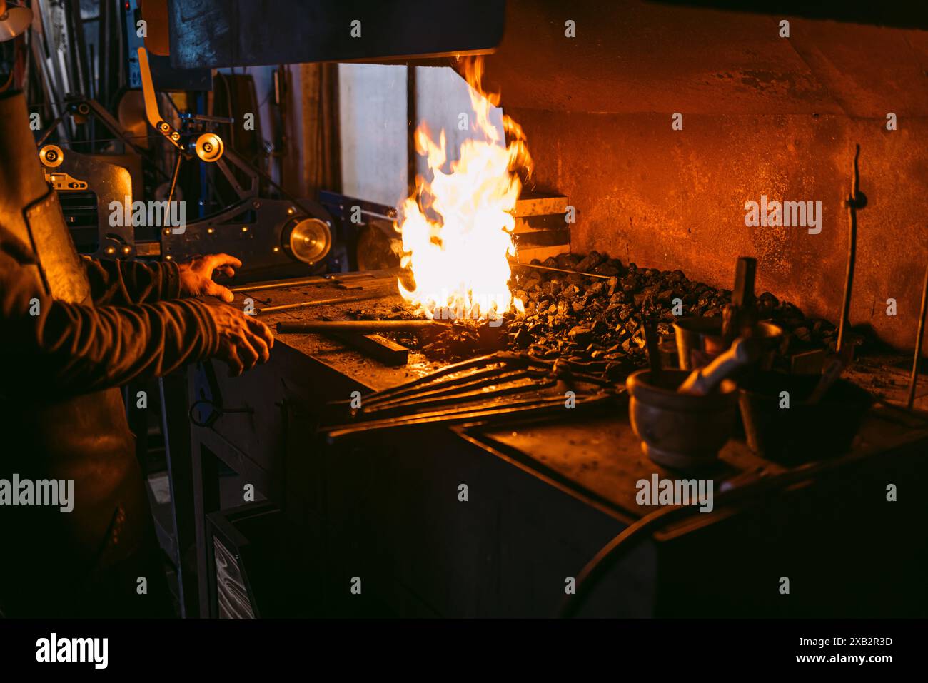 A cropped unrecognizable blacksmith's hand forging metalwork in the ...