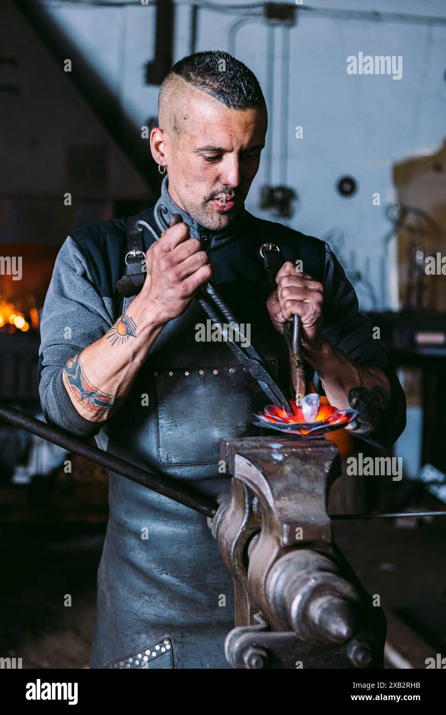 Male blacksmith forging metal with hammer in traditional workshop Stock ...