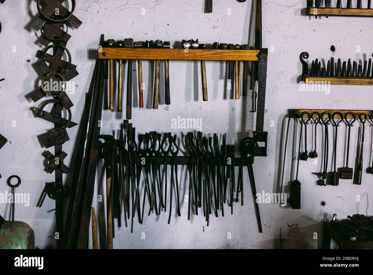 A variety of vintage blacksmithing tools neatly organized on a white ...