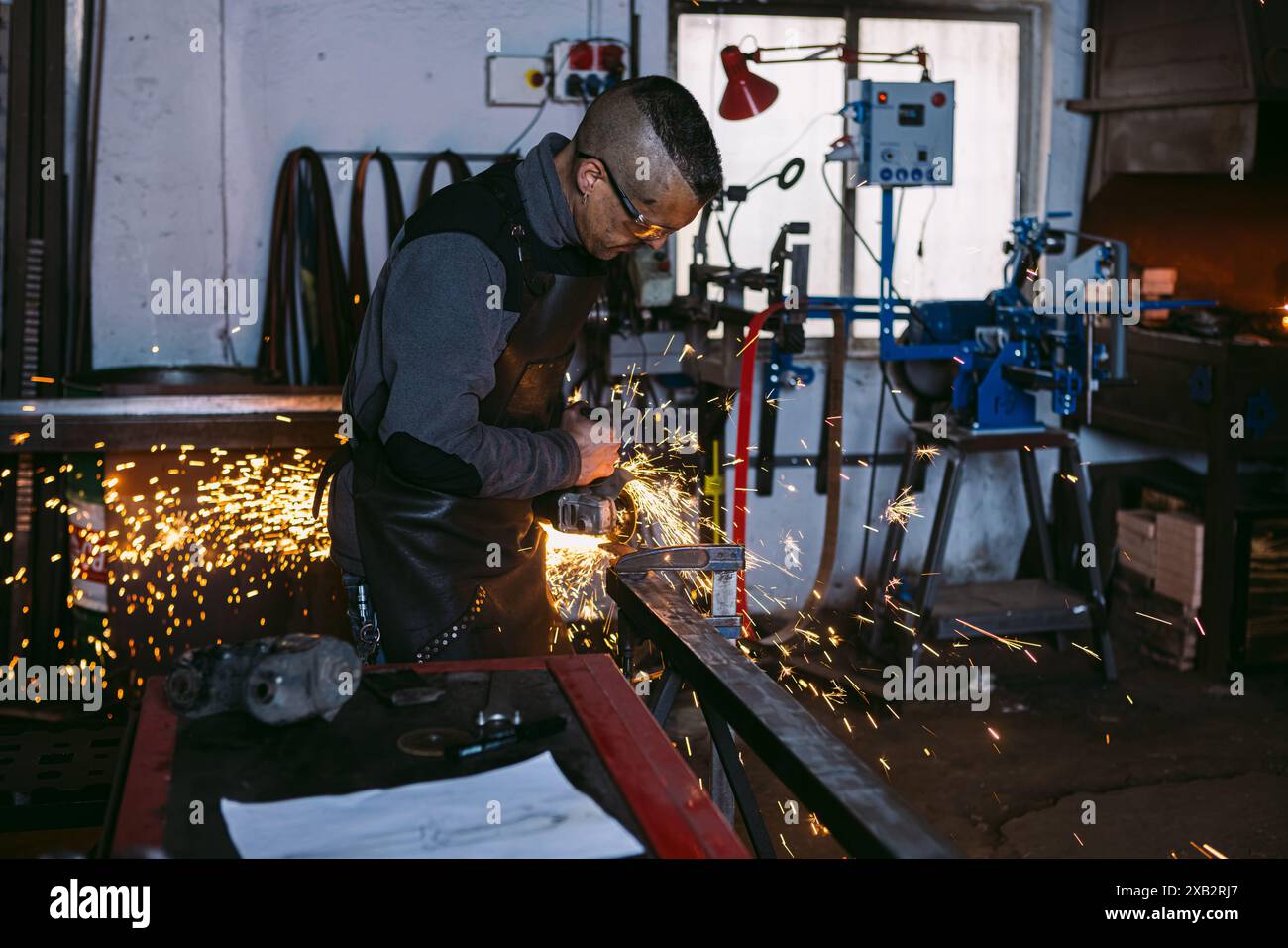 Blacksmith working with an angle grinder on a steel structure, creating ...