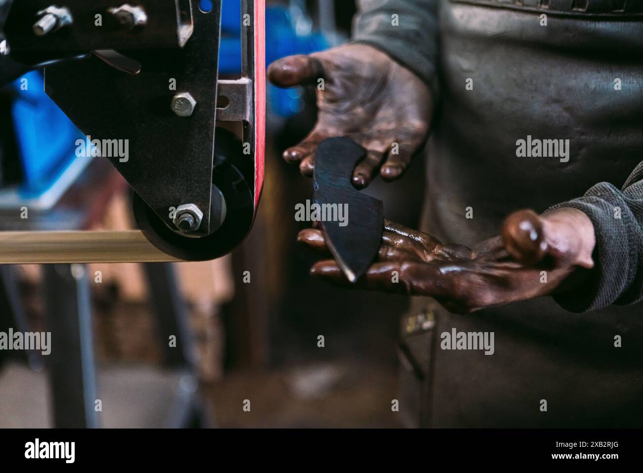 A cropped unrecognizable blacksmith is meticulously sharpening a metal ...