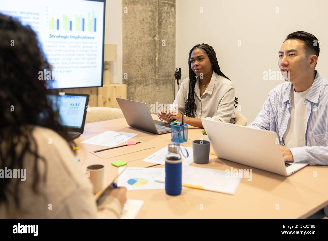 A team of diverse friends engage in a collaborative work session in a coworking space, focusing ...