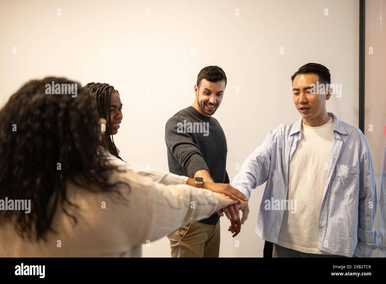 A diverse group of friends forming a team huddle in a modern coworking ...
