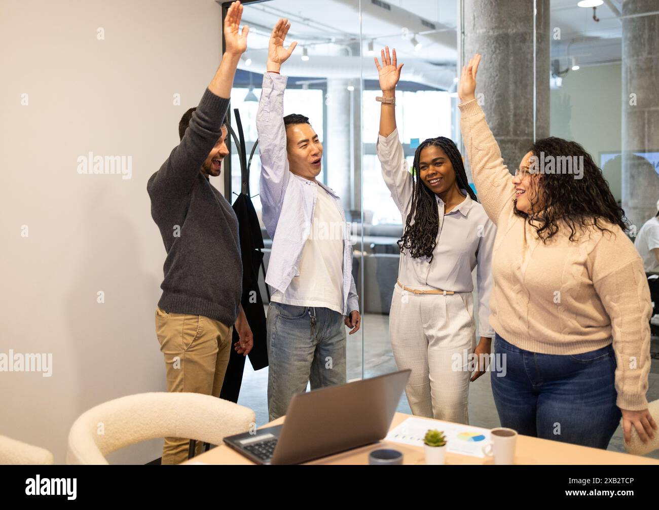 Group of diverse friends high-fiving in a modern coworking space ...