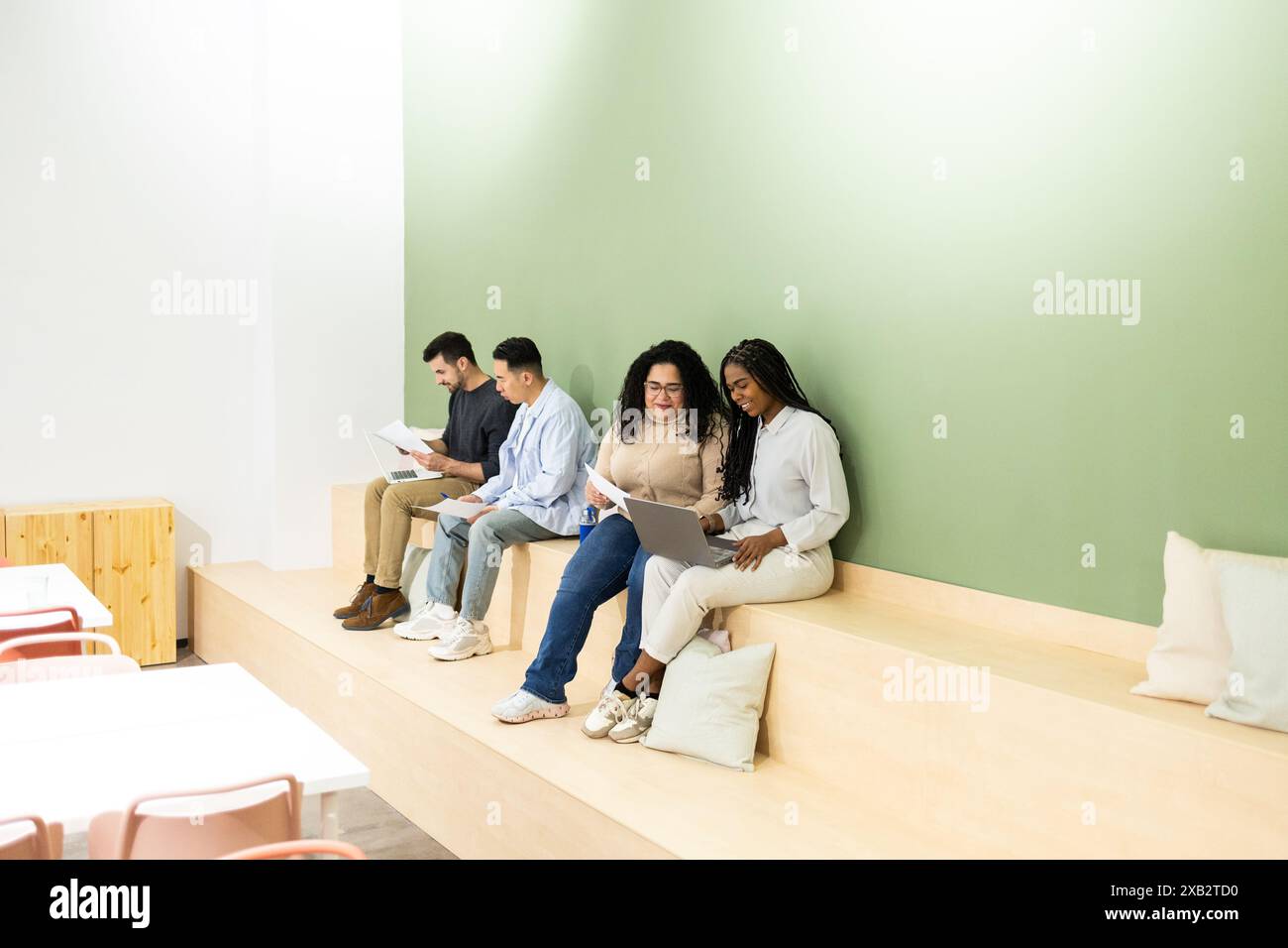 A multi-ethnic group of friends or colleagues work side by side on a ...