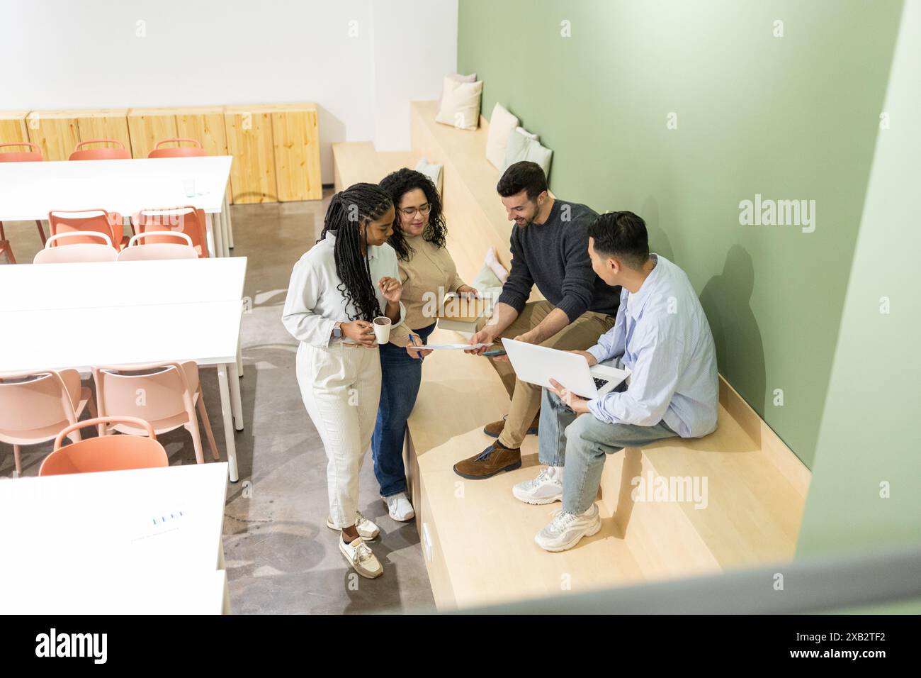 A diverse group of friends engage in a team discussion in a brightly ...