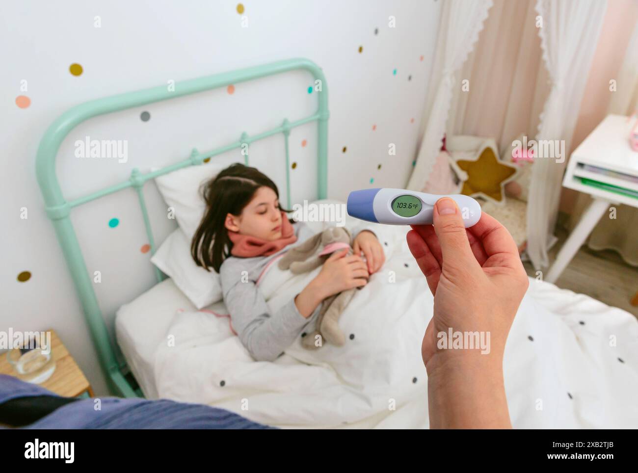 Adult hand holding a digital thermometer with a high fever reading in ...