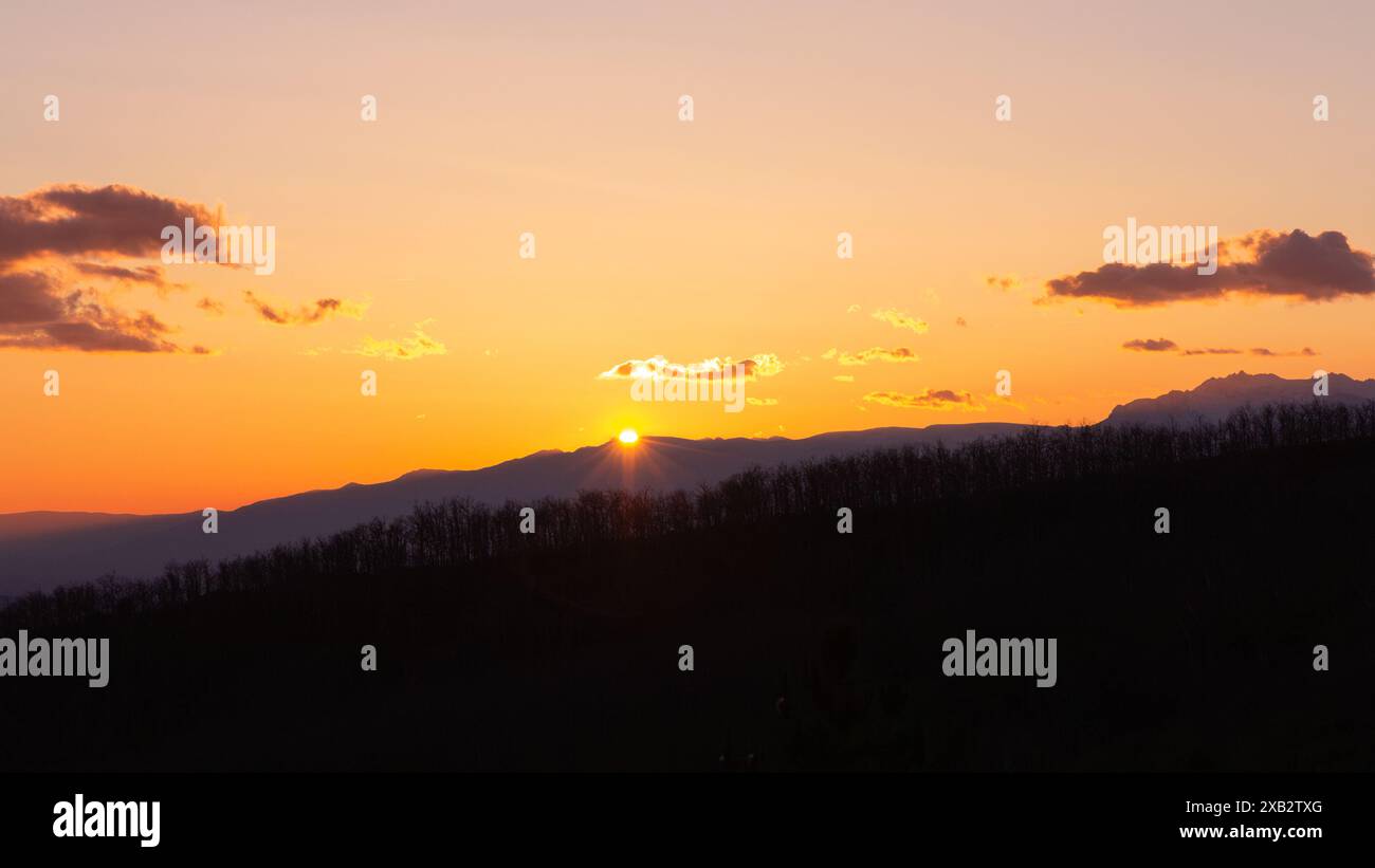 A stunning scene of the sun setting behind a mountain range, casting a ...