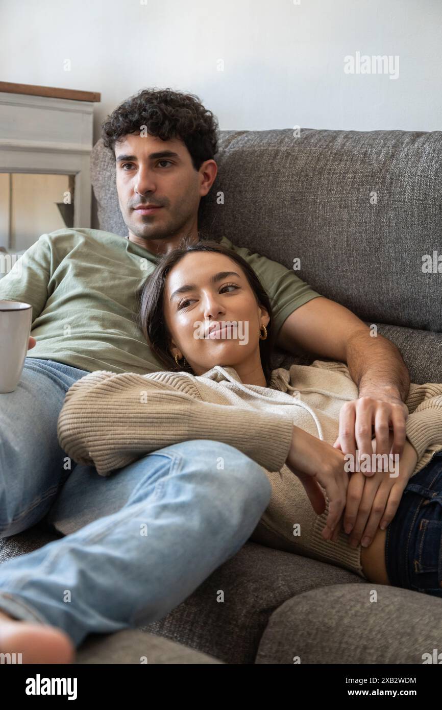 A loving couple lounges comfortably on a sofa, sharing an intimate ...