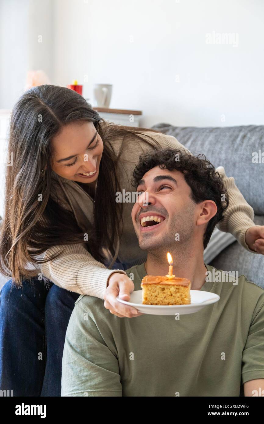A delighted woman surprises her partner with a birthday cake, both ...