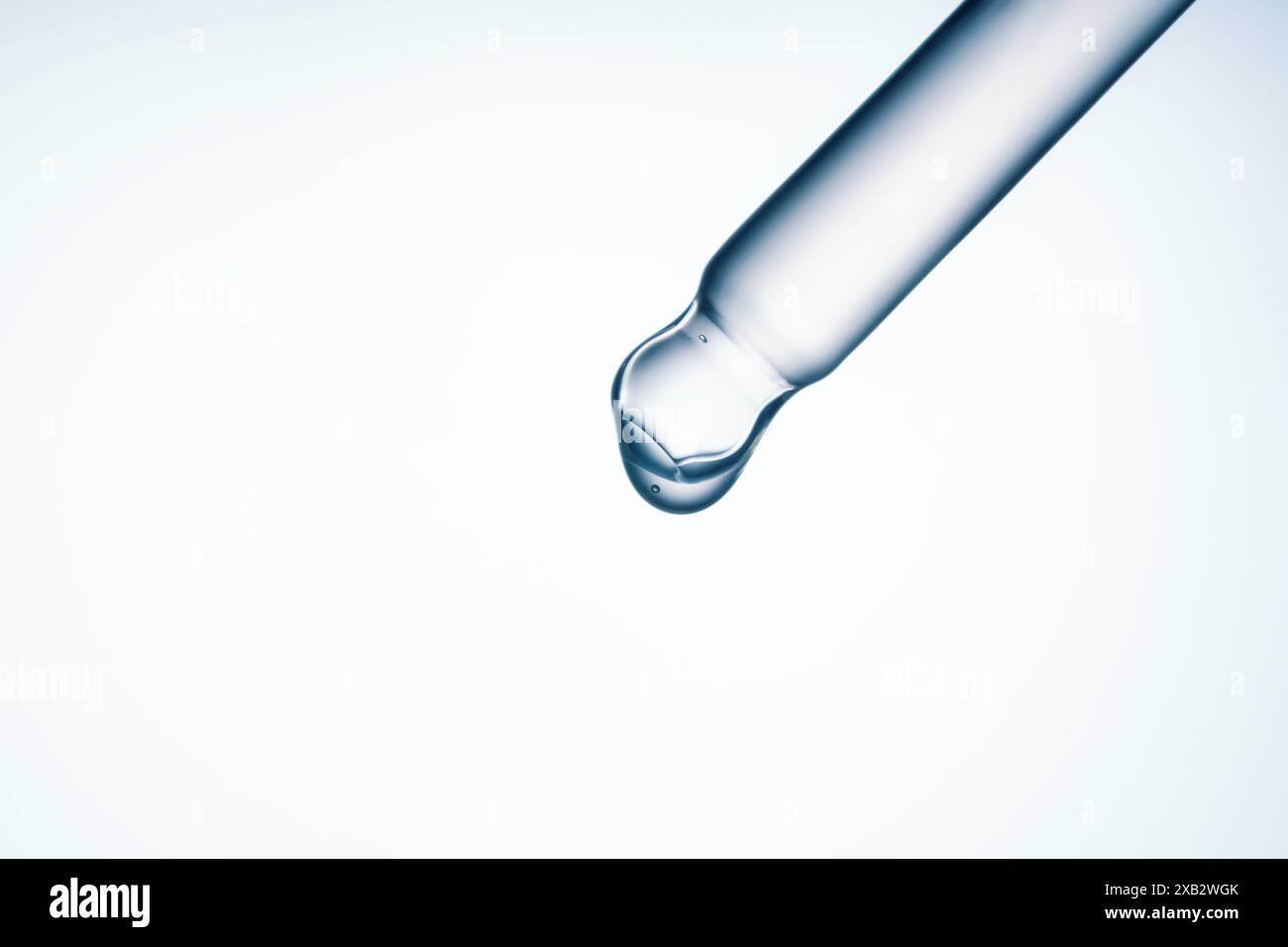 Close-up image of a cosmetic dropper with a single drop at the tip ...