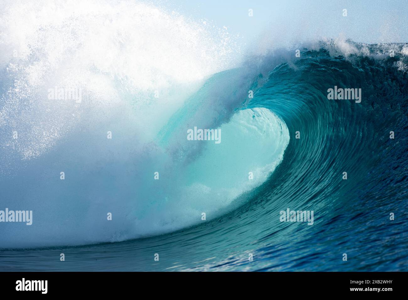 A powerful Teahupoo wave, famous for surfing, looms with crystal blue ...
