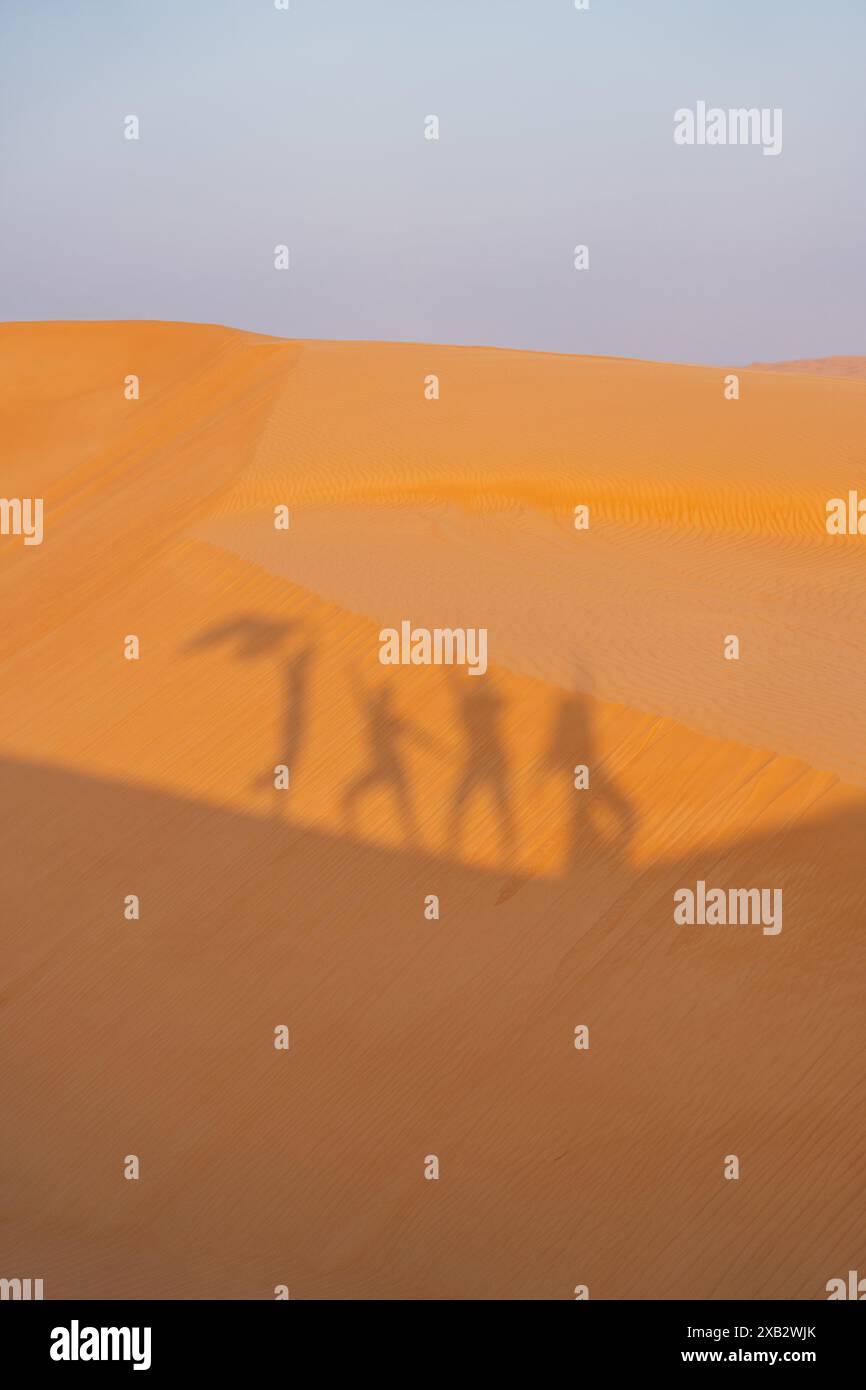 Shadows of a group of explorers cast on the smooth sand of a desert ...