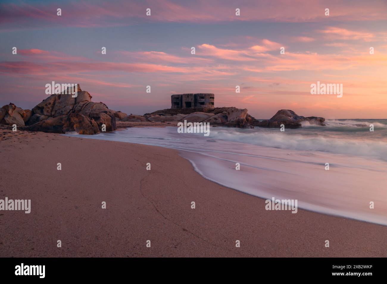 Pink sunset sky casting soft light over Atlanterra Beach Bunker ruins ...