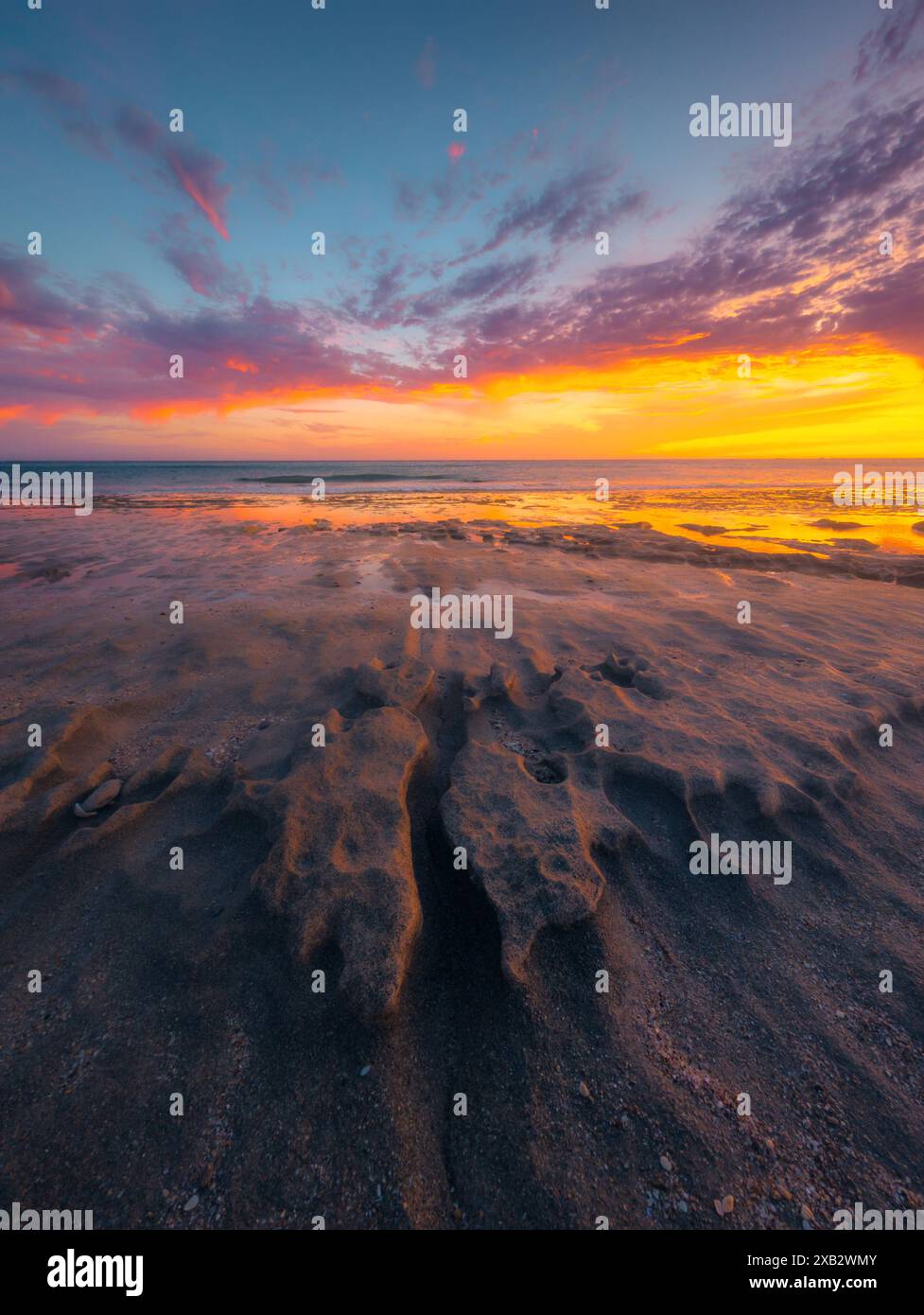 Golden sunset casts vibrant hues over Atlanterra Beach with textured ...