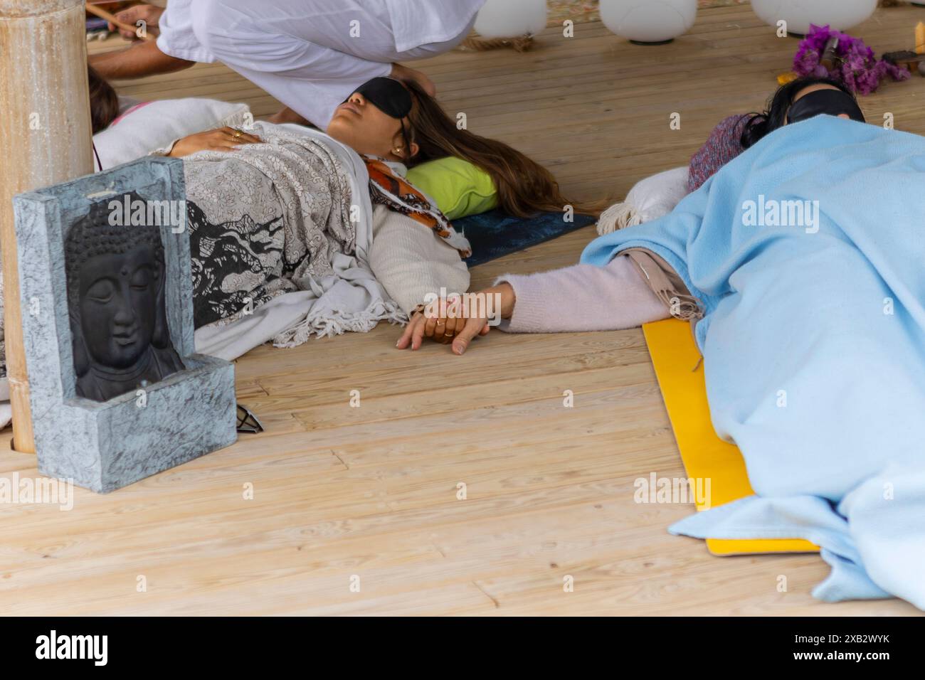 Unrecognizable women partake in a sound therapy session, lying down ...