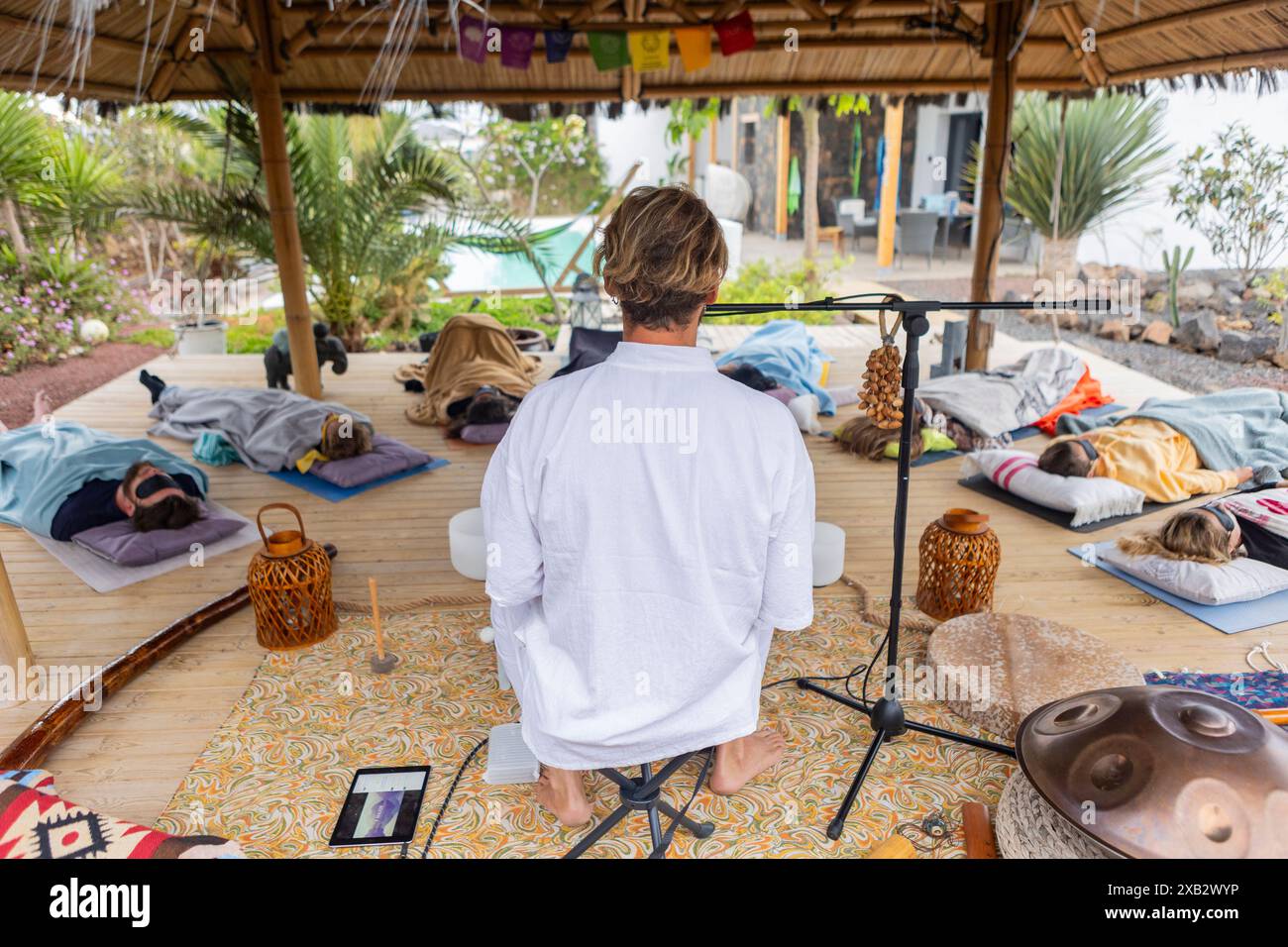 Back view of unrecognizable male instructor leads a sound therapy class ...