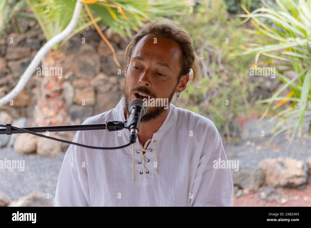 A man in a white shirt sings soulfully into a microphone, surrounded by ...