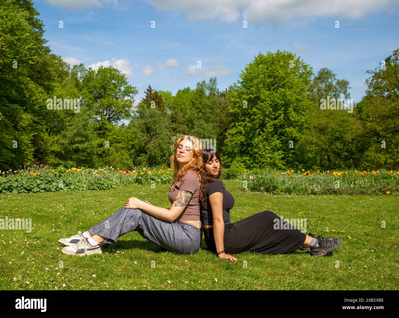 Two friends enjoy a peaceful moment together, sitting back-to-back in a ...